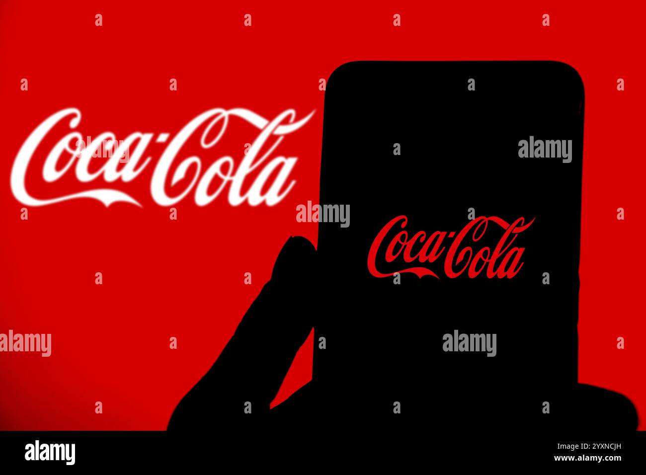 Coca-Cola logo is seen on a mobile phone and a computer screen Stock ...
