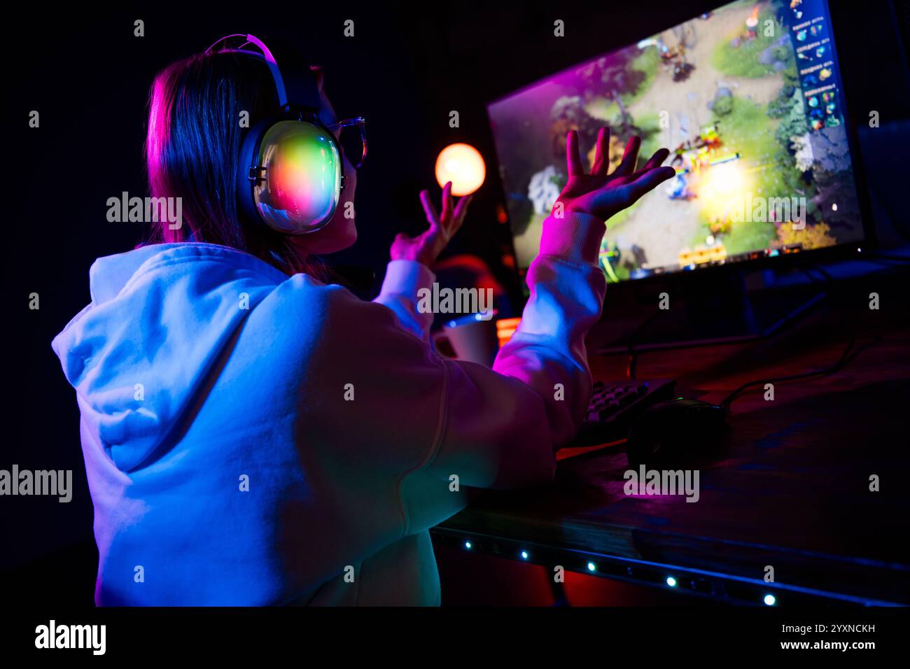 Young female gamer enjoying an intense video game session under neon ...