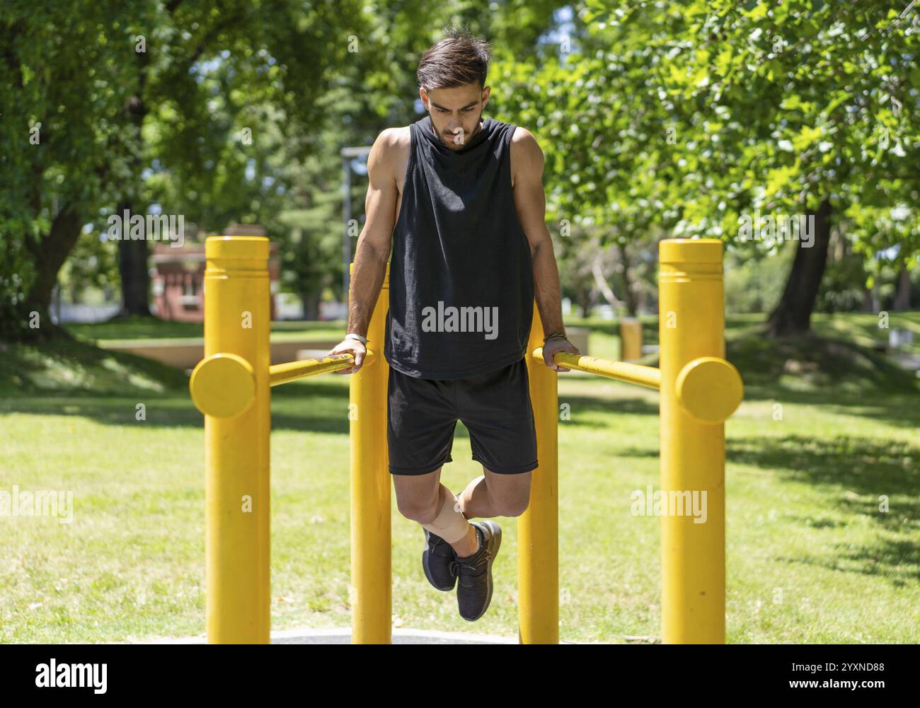 Fit young man executing dips on outdoor parallel bars in the park Stock ...