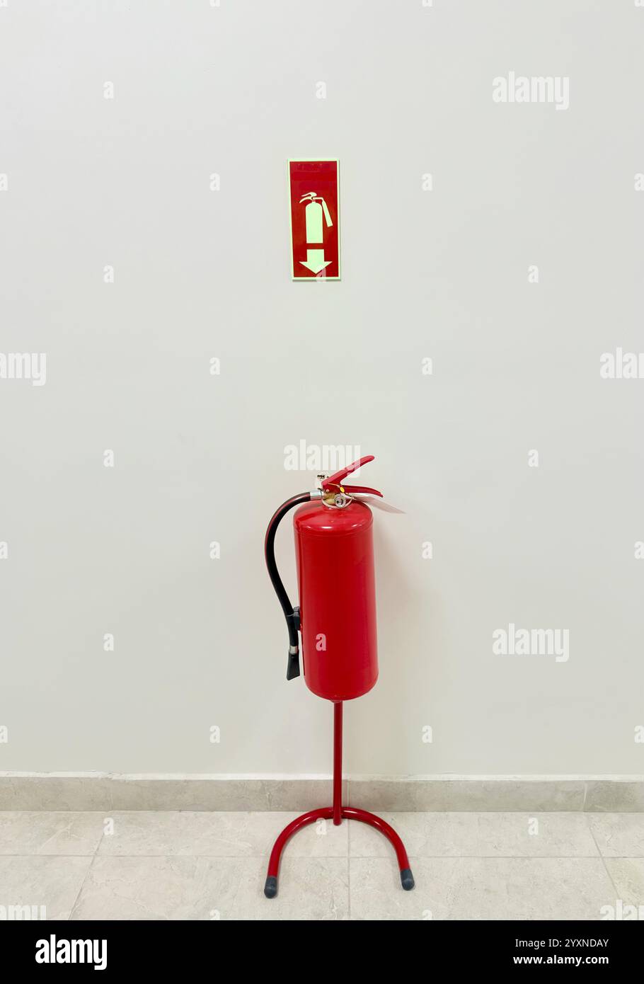 A red fire extinguisher placed below an exit sign on a white wall Stock ...