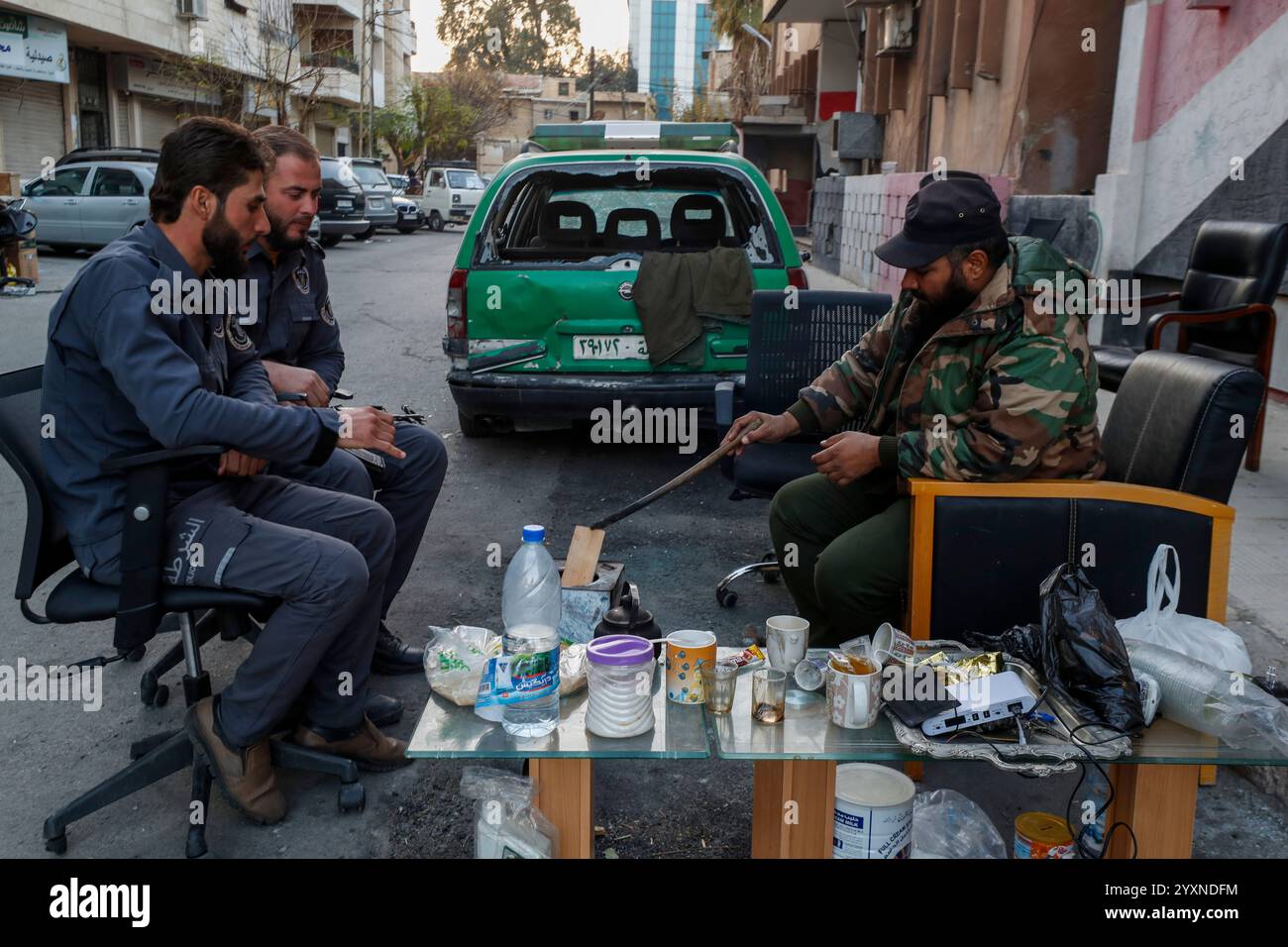 Syrian fighters sit in a street as they guard a police station in ...
