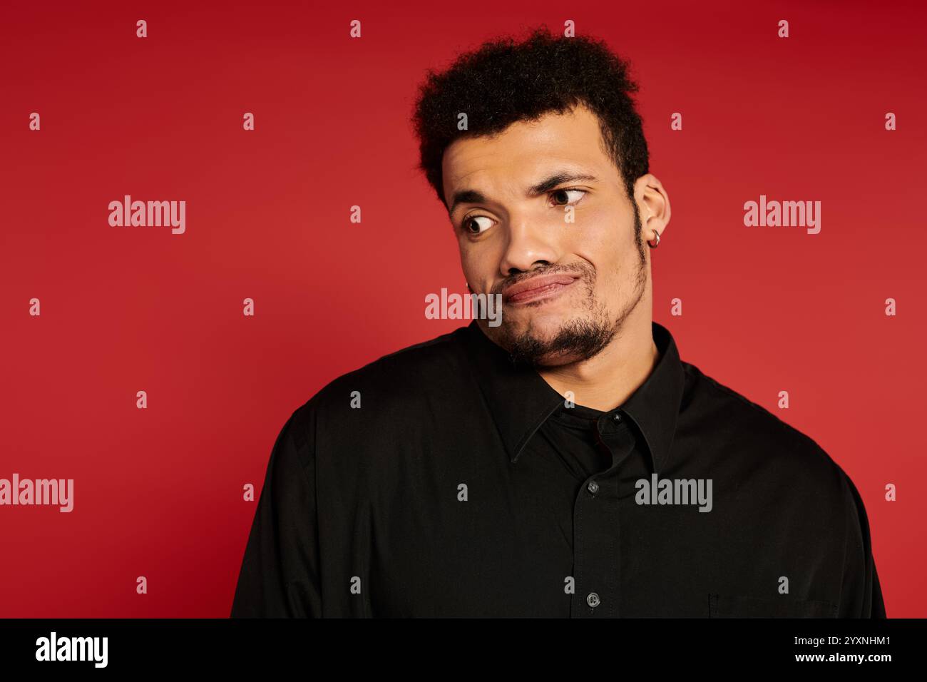 A handsome young man displays a curious expression in front of a bold ...