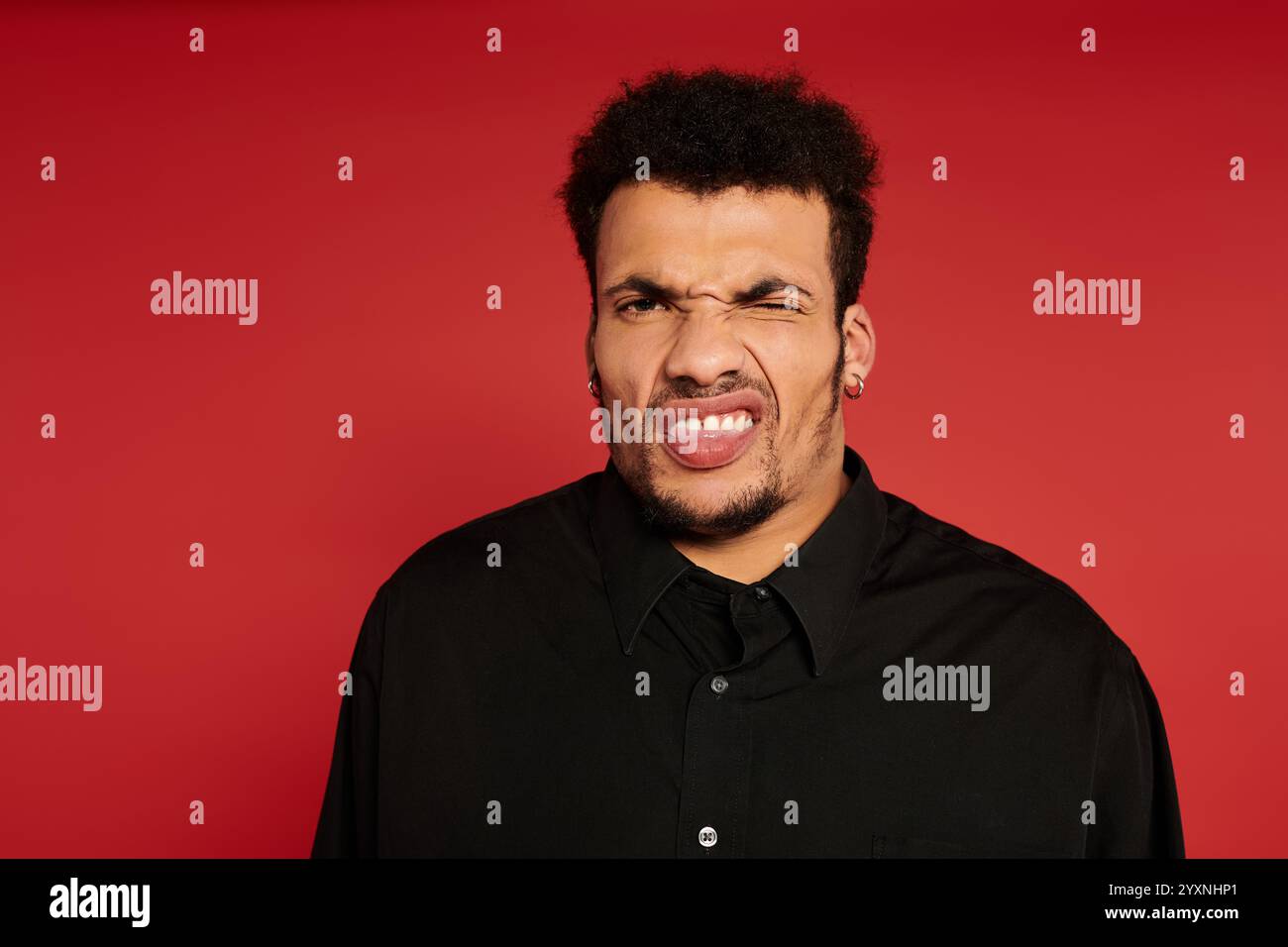 A handsome young man poses playfully with a silly expression in a ...