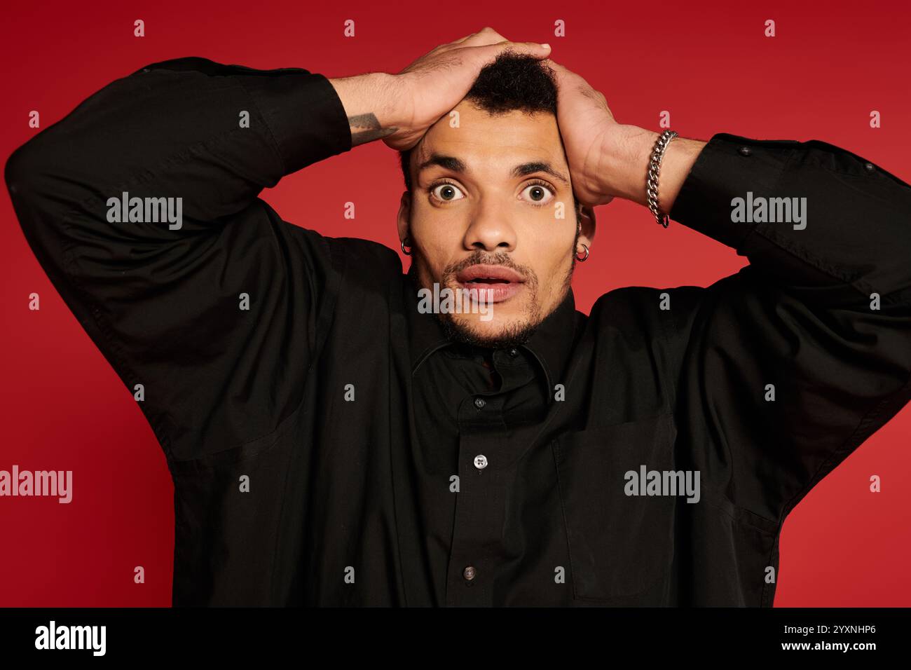 A young handsome man holds his head in shock, showcasing his expressive ...