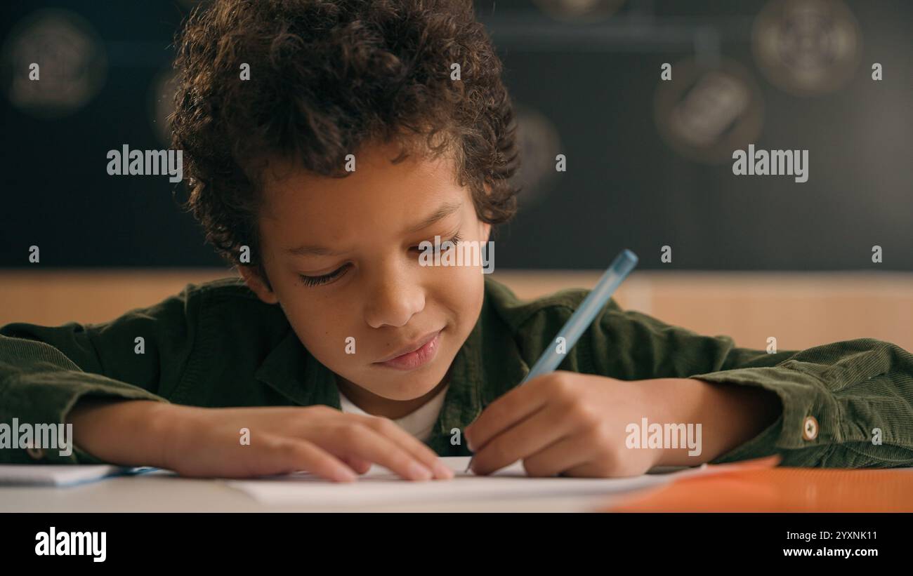 Little African American guy boy writing notes task class lesson primary ...