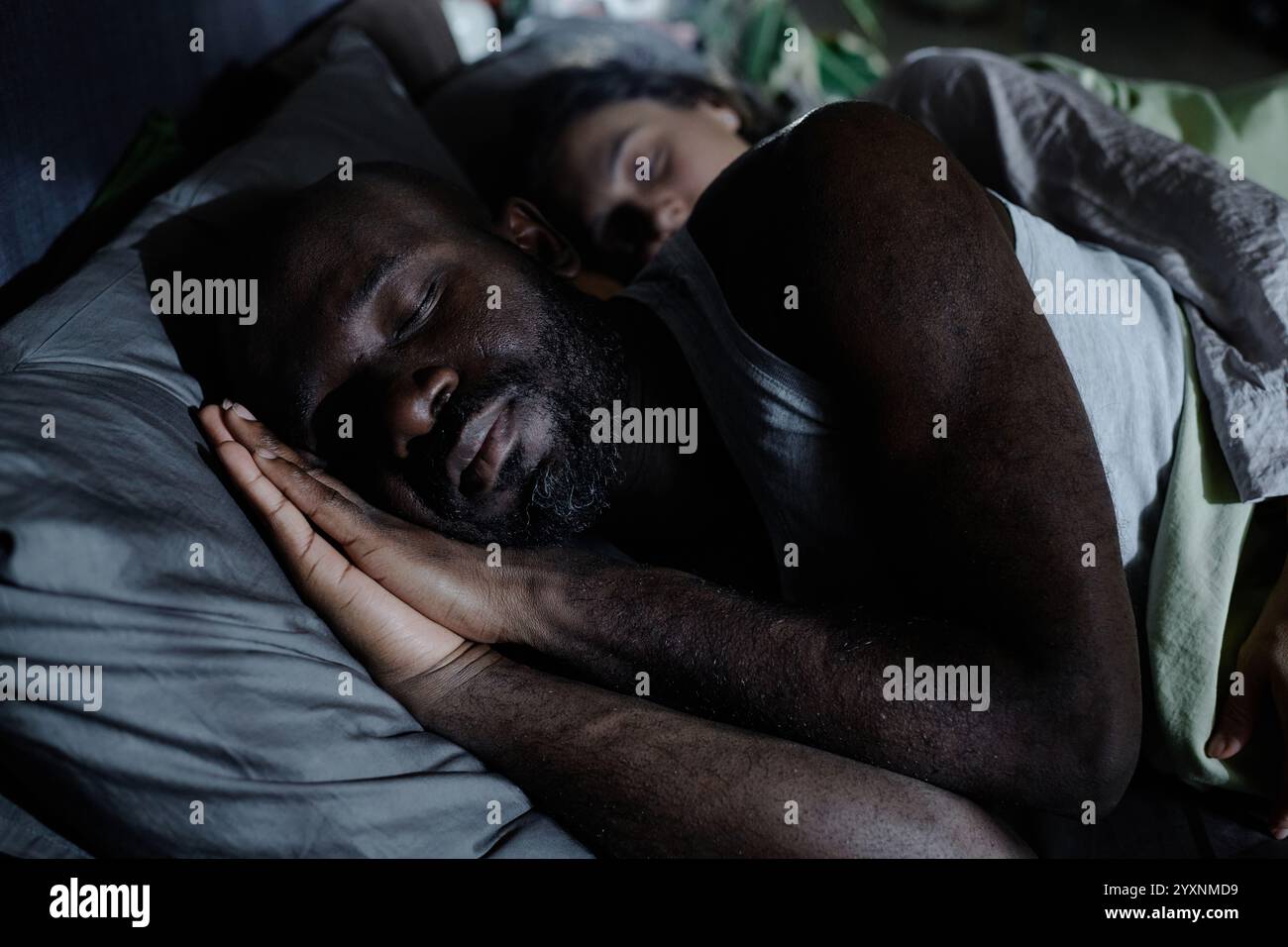 Medium close up of African American man sleeping easy while his wife ...