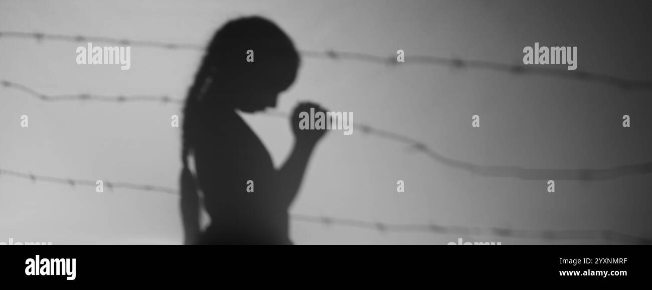 Shadow of little Jewish girl behind barbed wire on grey background ...