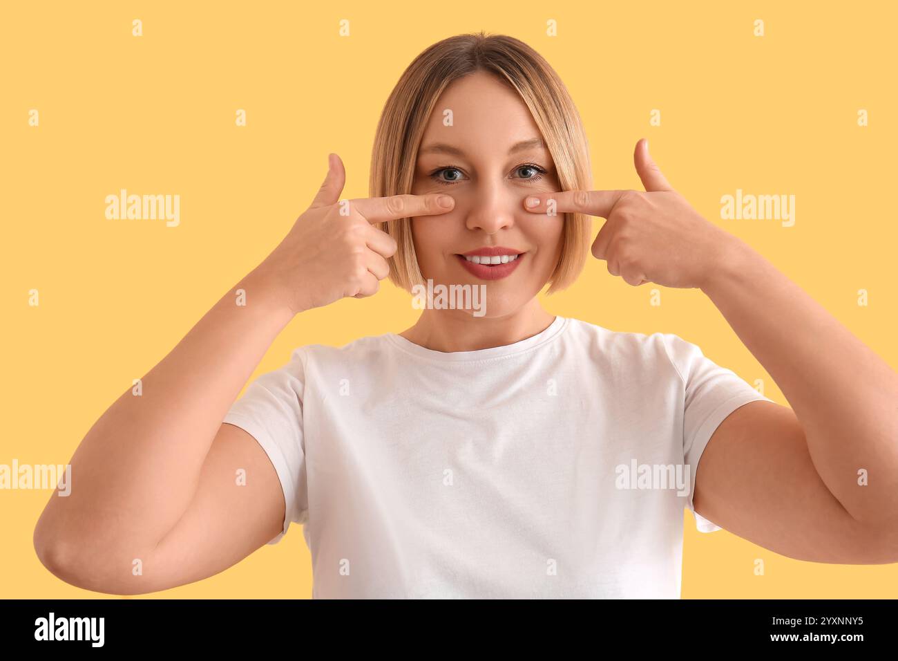 Woman doing face building exercise on yellow background Stock Photo - Alamy