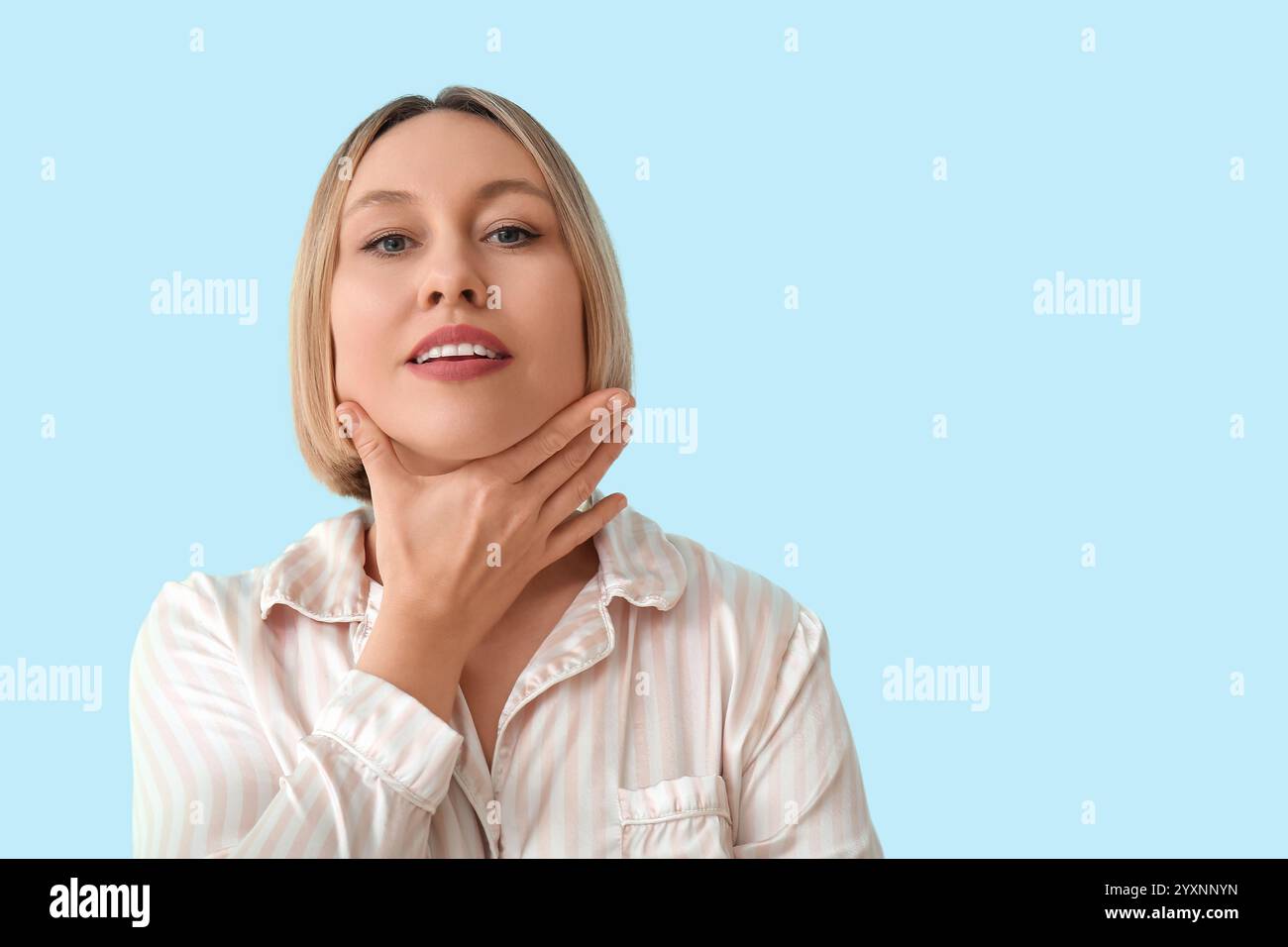 Woman doing face building exercise on blue background Stock Photo - Alamy