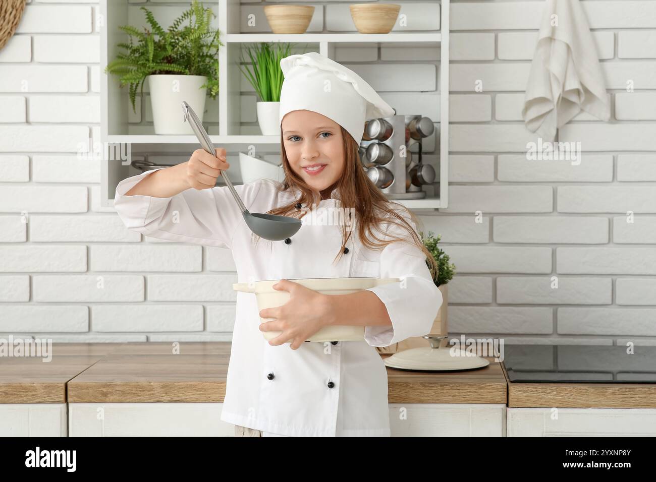 Cute little happy chef with cooking pot and ladle in kitchen at home ...