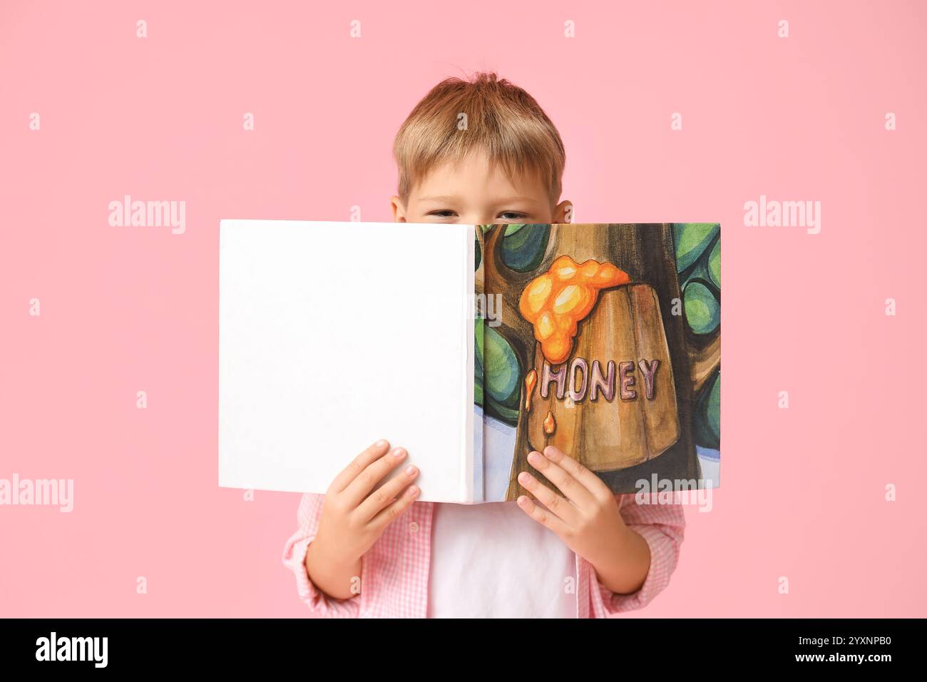 Cute little boy hiding face behind book on pink background Stock Photo ...
