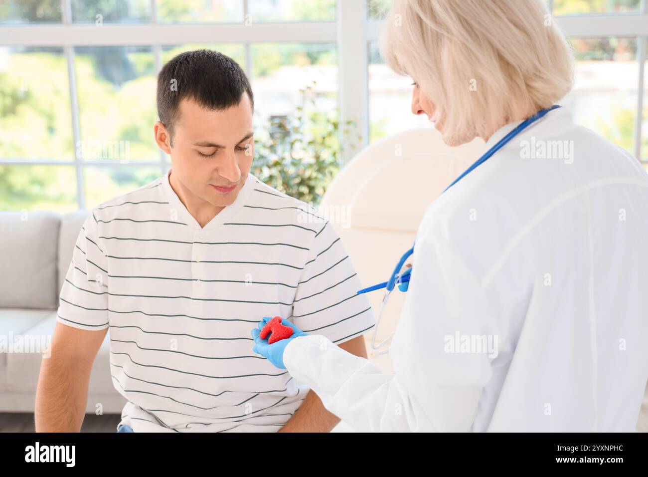 Female endocrinologist showing thyroid gland model to male patient in ...