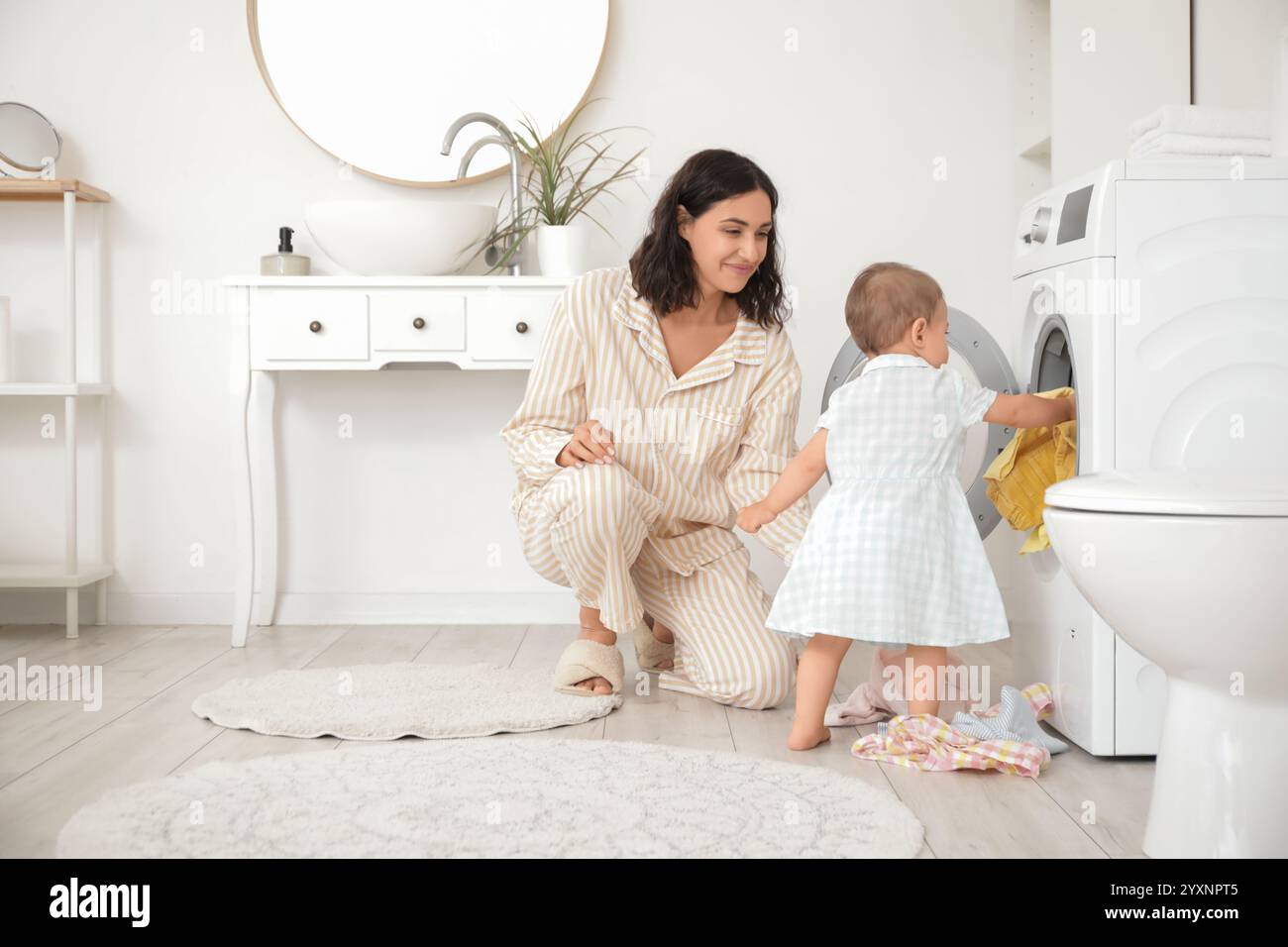 Mother with her little baby doing laundry at home Stock Photo - Alamy
