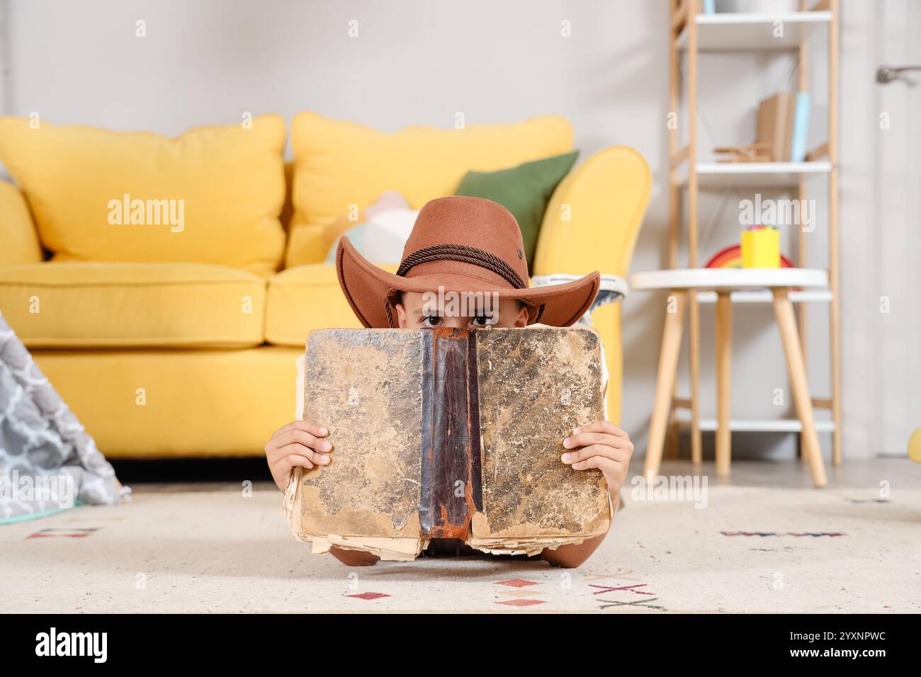 Cute little cowboy reading book at home Stock Photo - Alamy