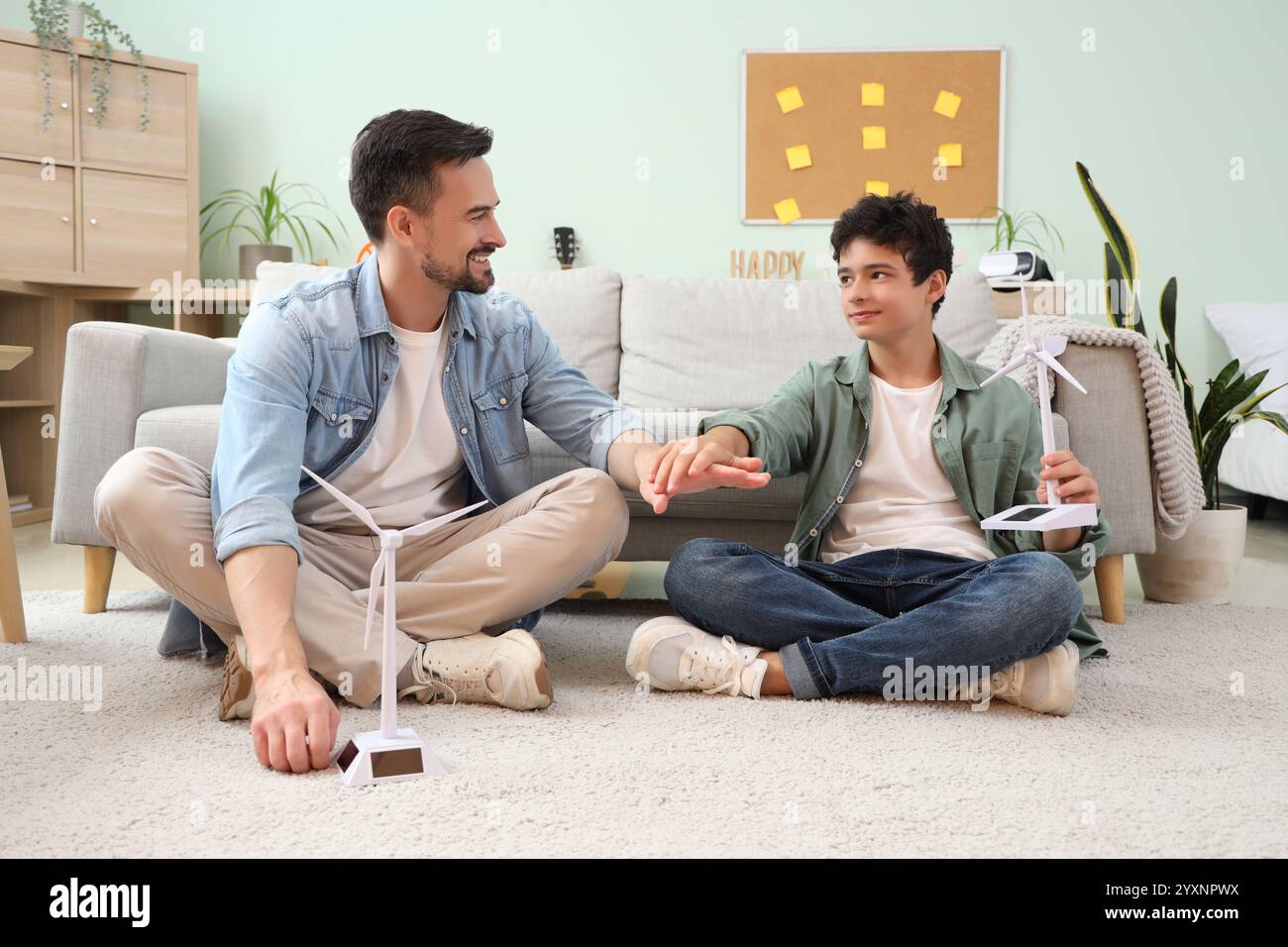 Teenage boy and his father with wind turbine models putting hands ...
