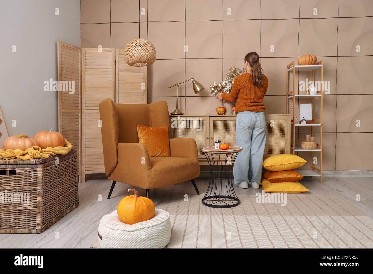 Young woman with autumn decor on commode at home, back view Stock Photo ...