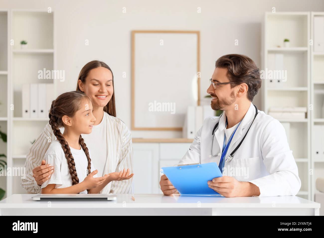 Male pediatrician working with girl and mother in clinic Stock Photo ...