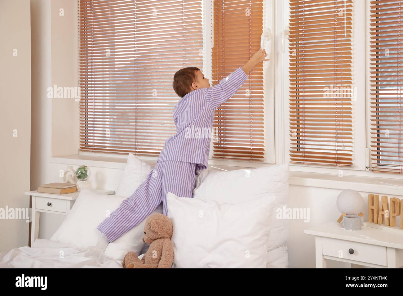 Cute little boy trying to open window in bedroom. Child at risk Stock ...