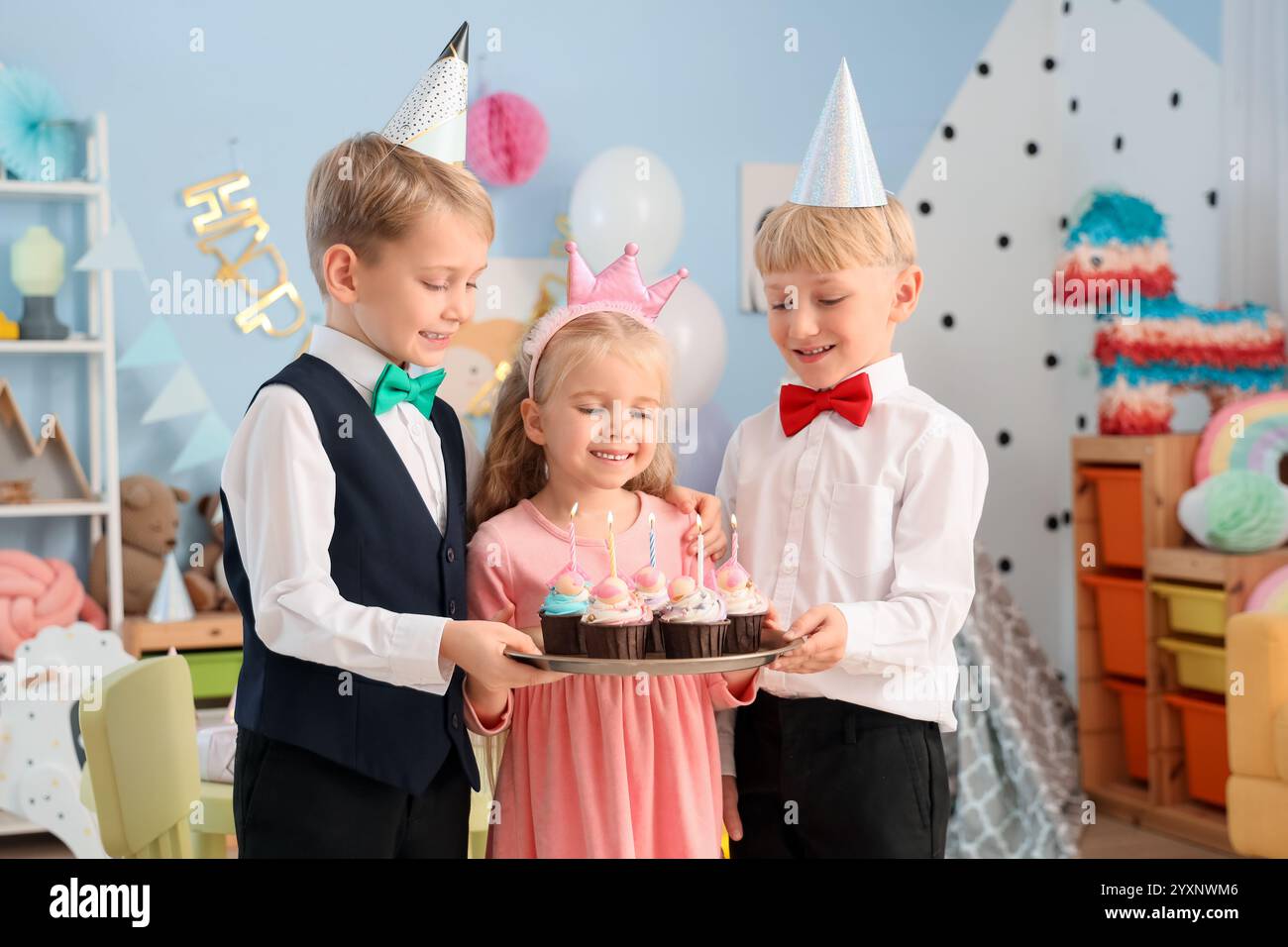 Cute little happy kids in party hats with cupcakes and candles ...