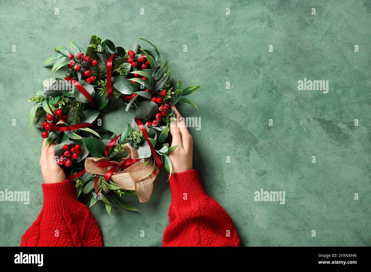 Female hands with beautiful mistletoe wreath on grunge green background ...