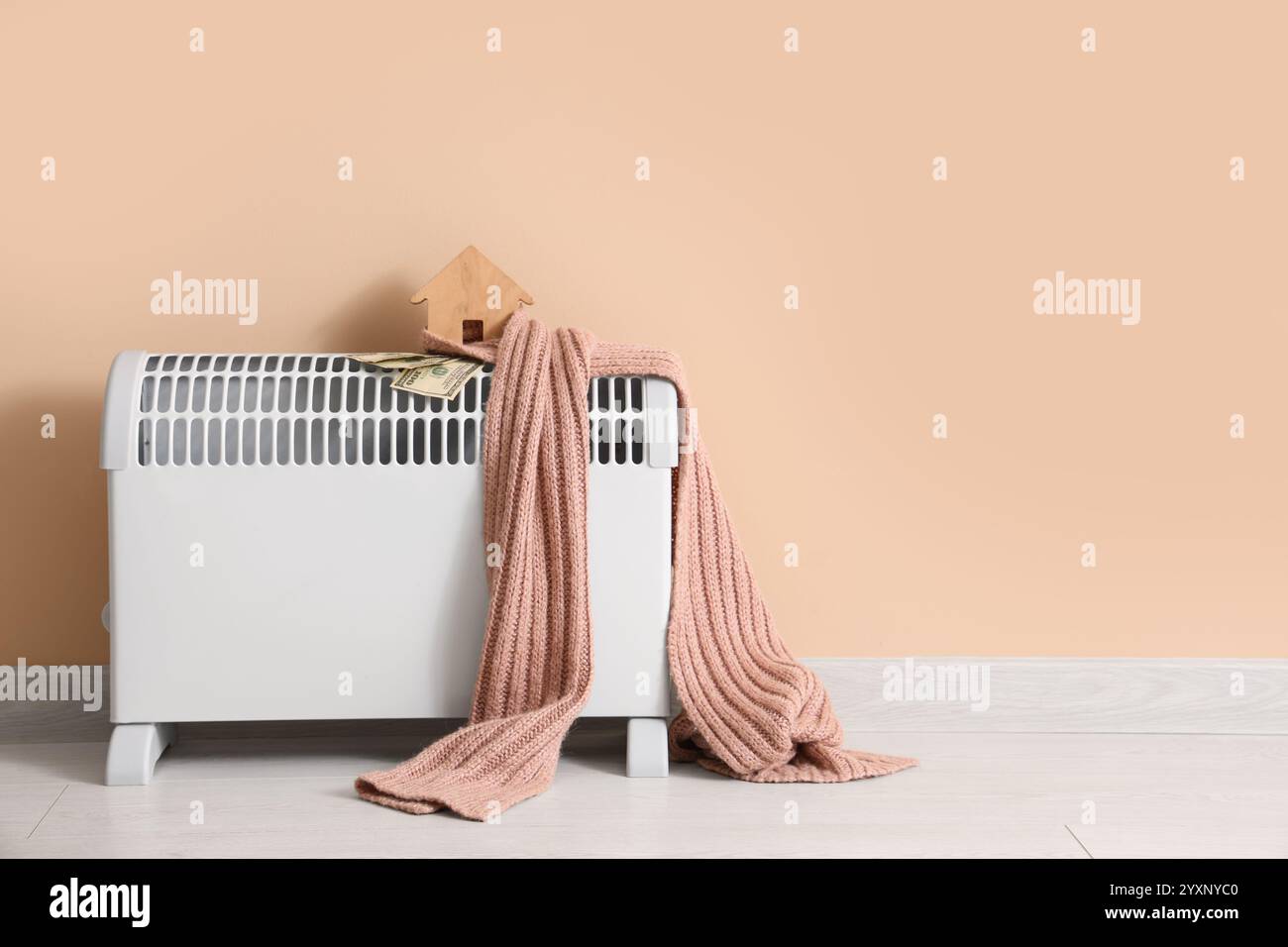 House model with warm scarf and money on convector heater against beige ...