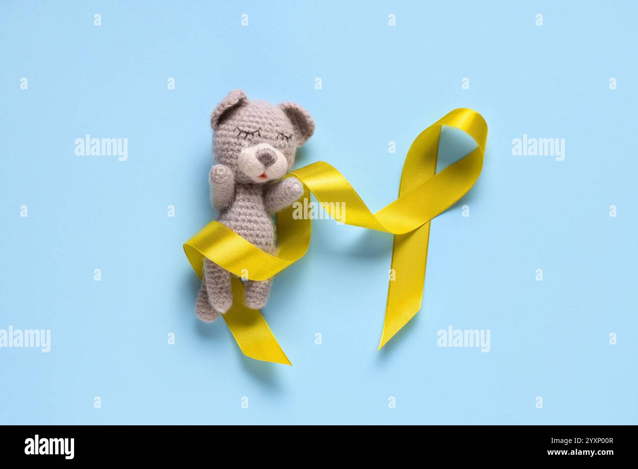 Teddy bear with yellow ribbon on color background. Childhood cancer ...