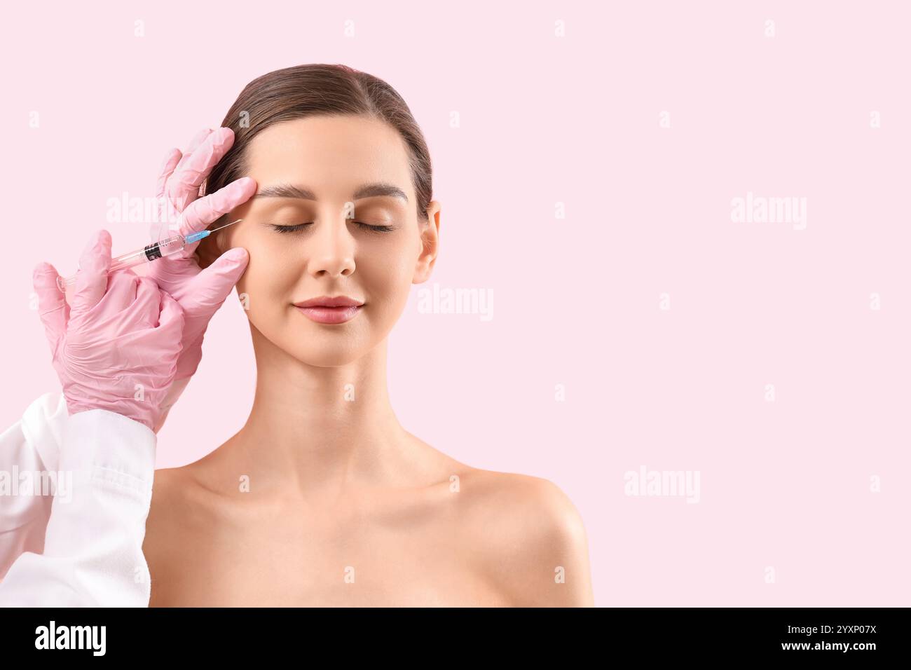 Young girl receiving filler injection in face against pink background ...