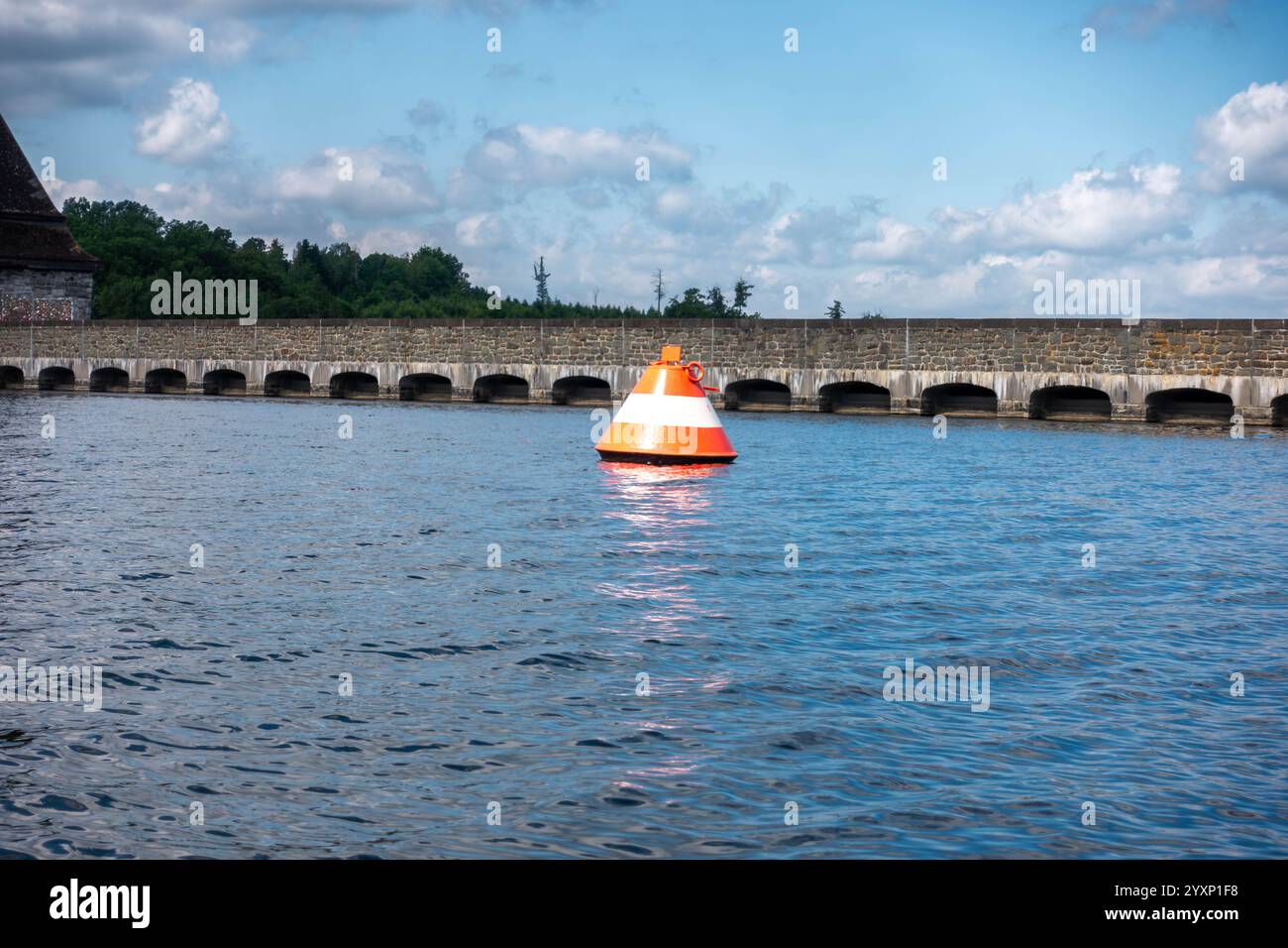 A buoy is floating in the water near a large body of water. The buoy is ...