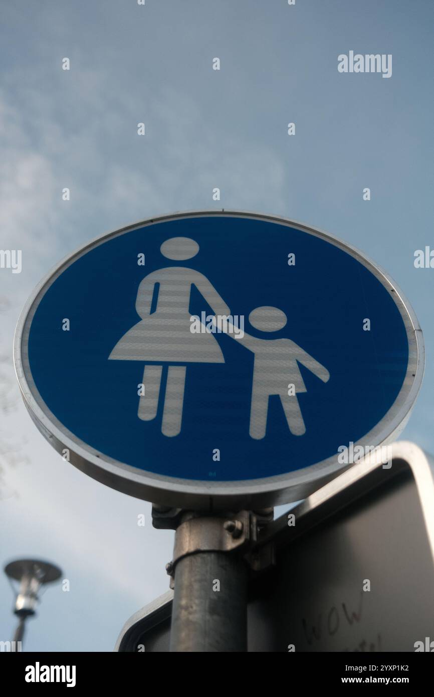 A blue sign with a woman and a child holding hands. The sign is on a ...