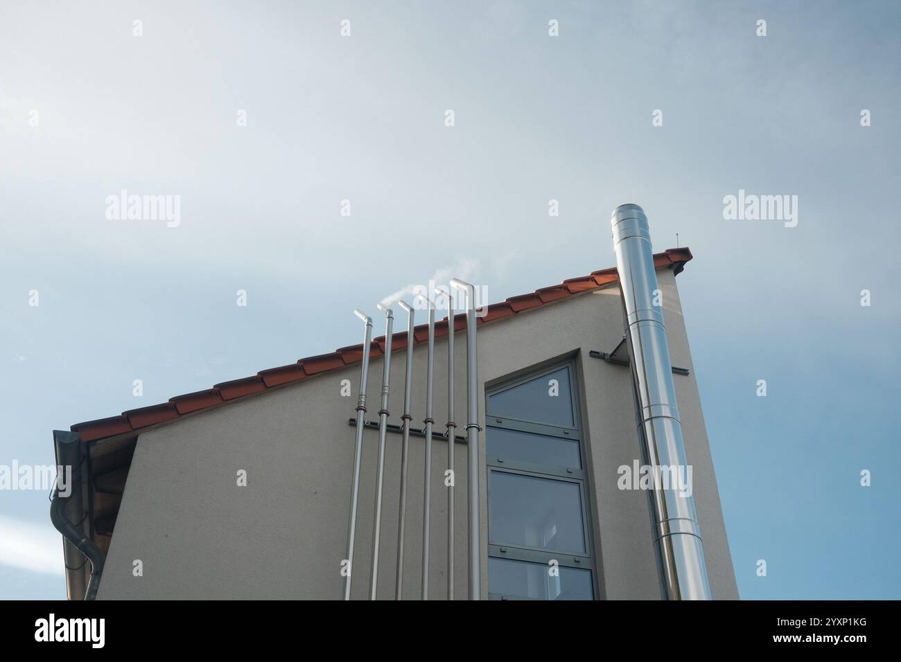 A building with a chimney on the roof. The chimney is tall and has a ...