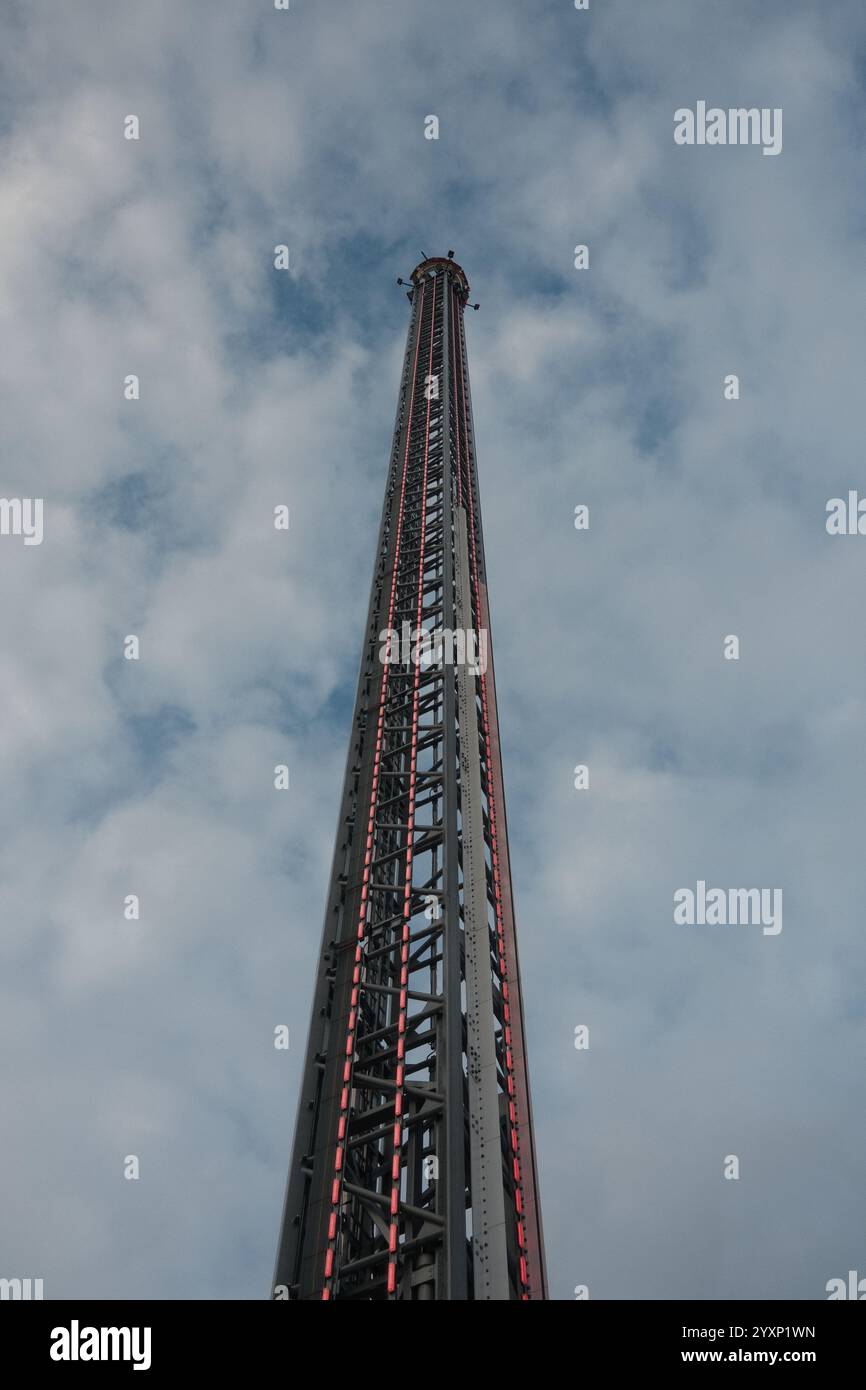 A tall tower with red and black stripes is seen against a blue sky. The ...