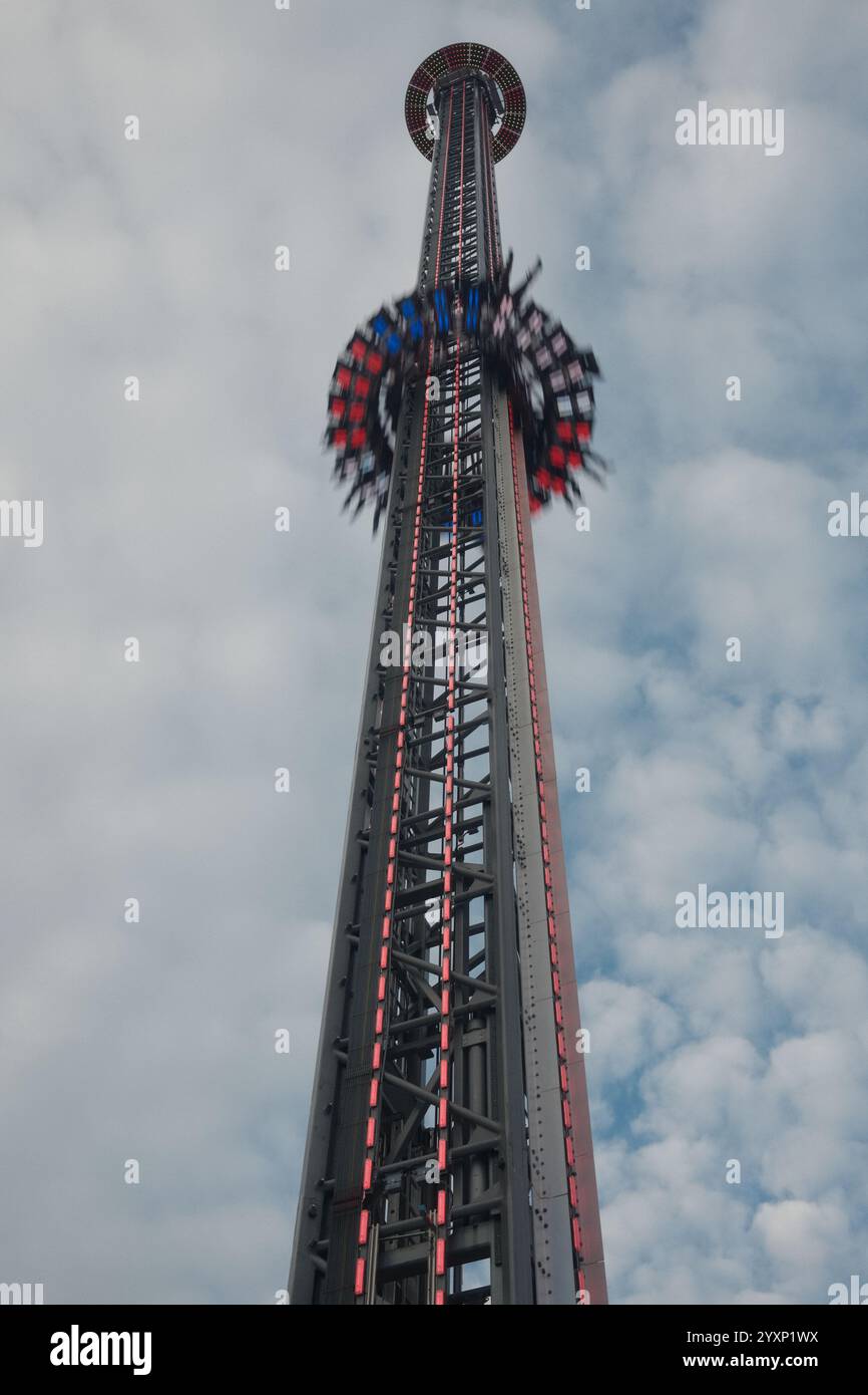 A tall tower with a red, blue and white design. The tower is lit up and ...