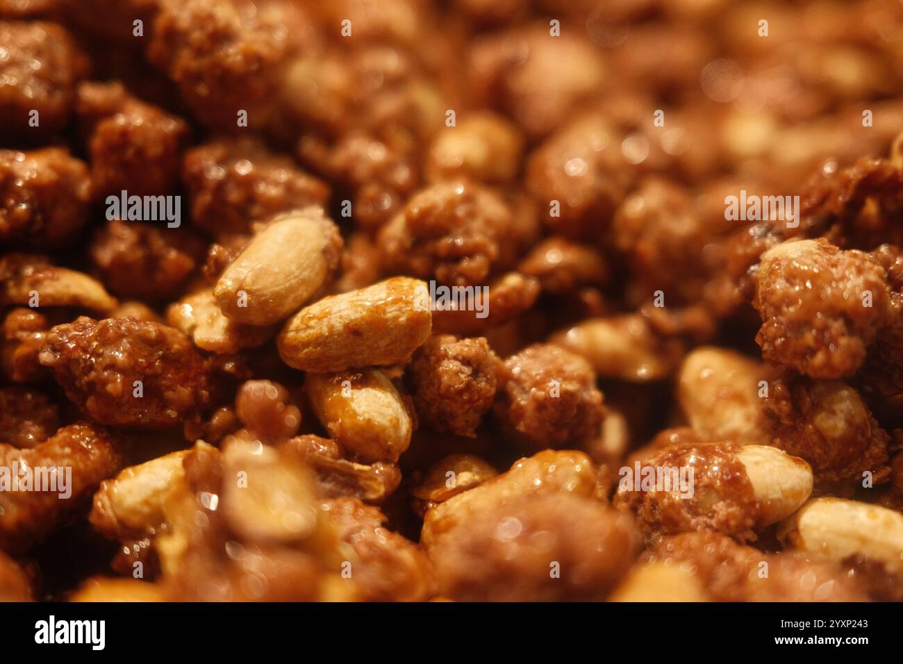 A close up of a pile of nuts, including peanuts, with a brownish color ...