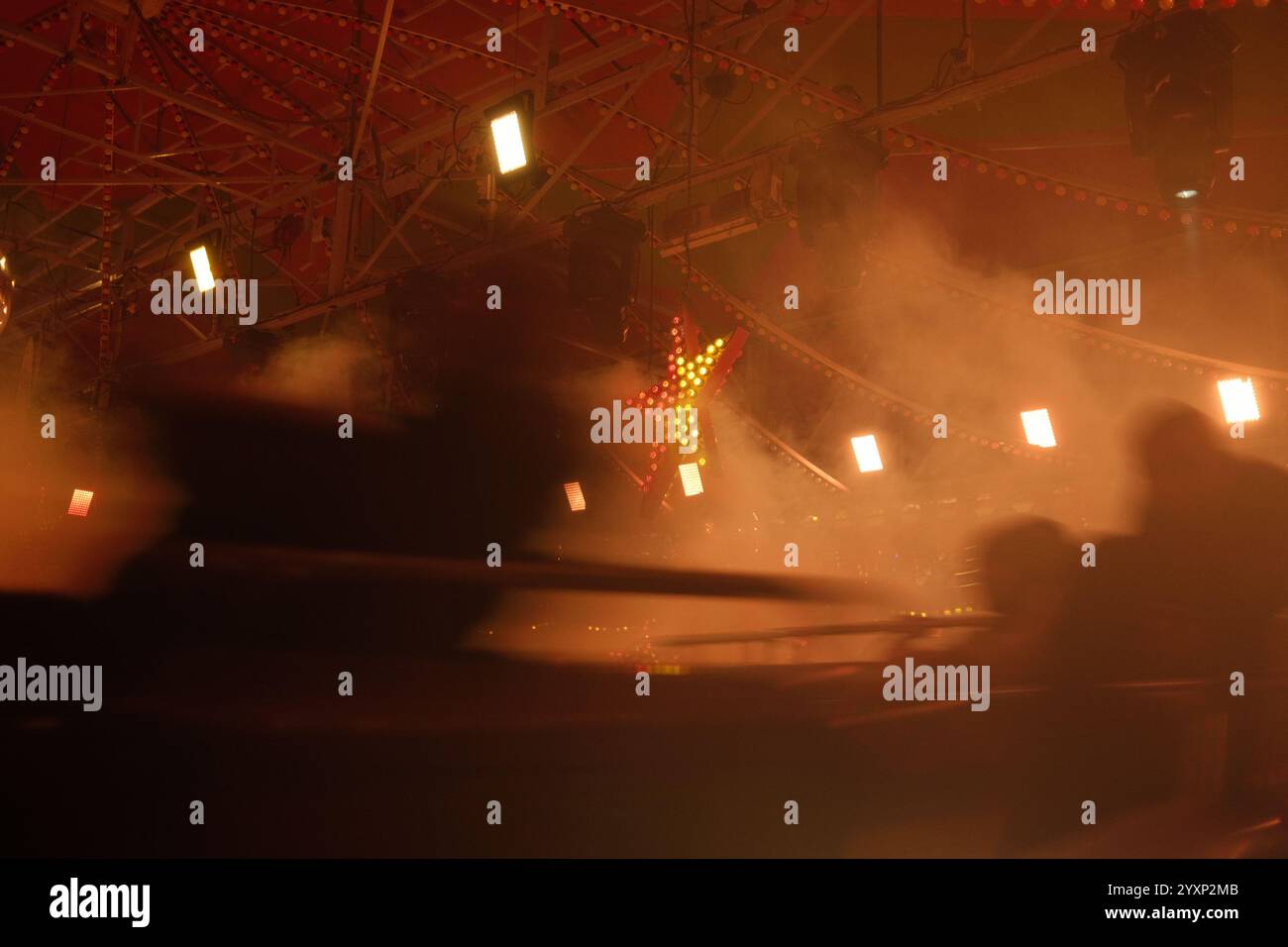 A circus tent with smoke and lights. A man is hanging from the ceiling ...