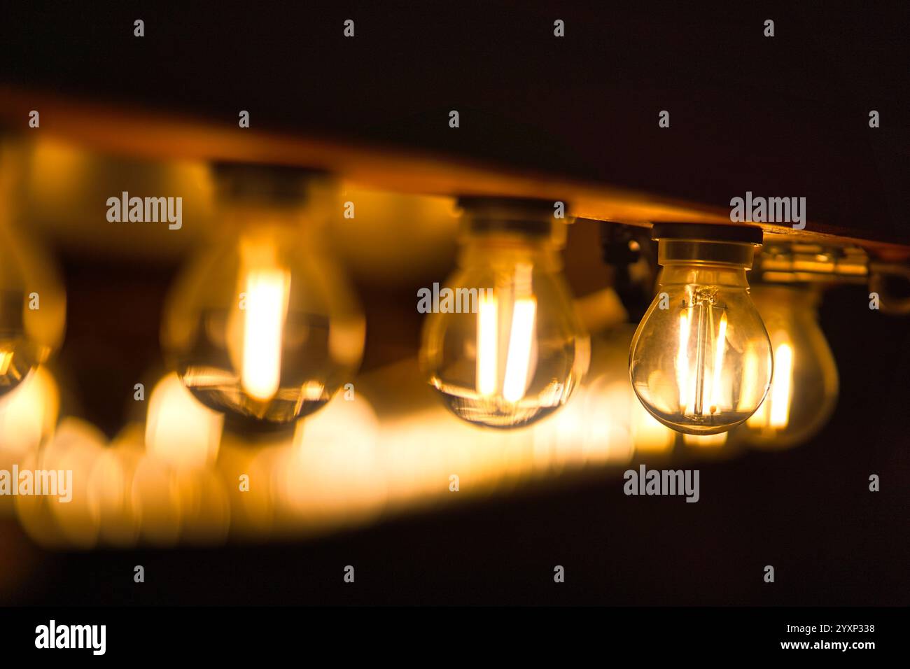 A bunch of light bulbs are lit up and hanging from the ceiling. The ...