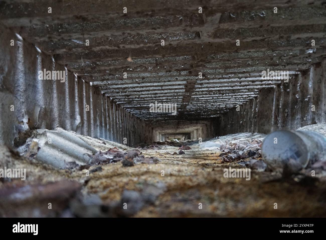 A long, narrow tunnel with a lot of debris and trash. The tunnel is ...