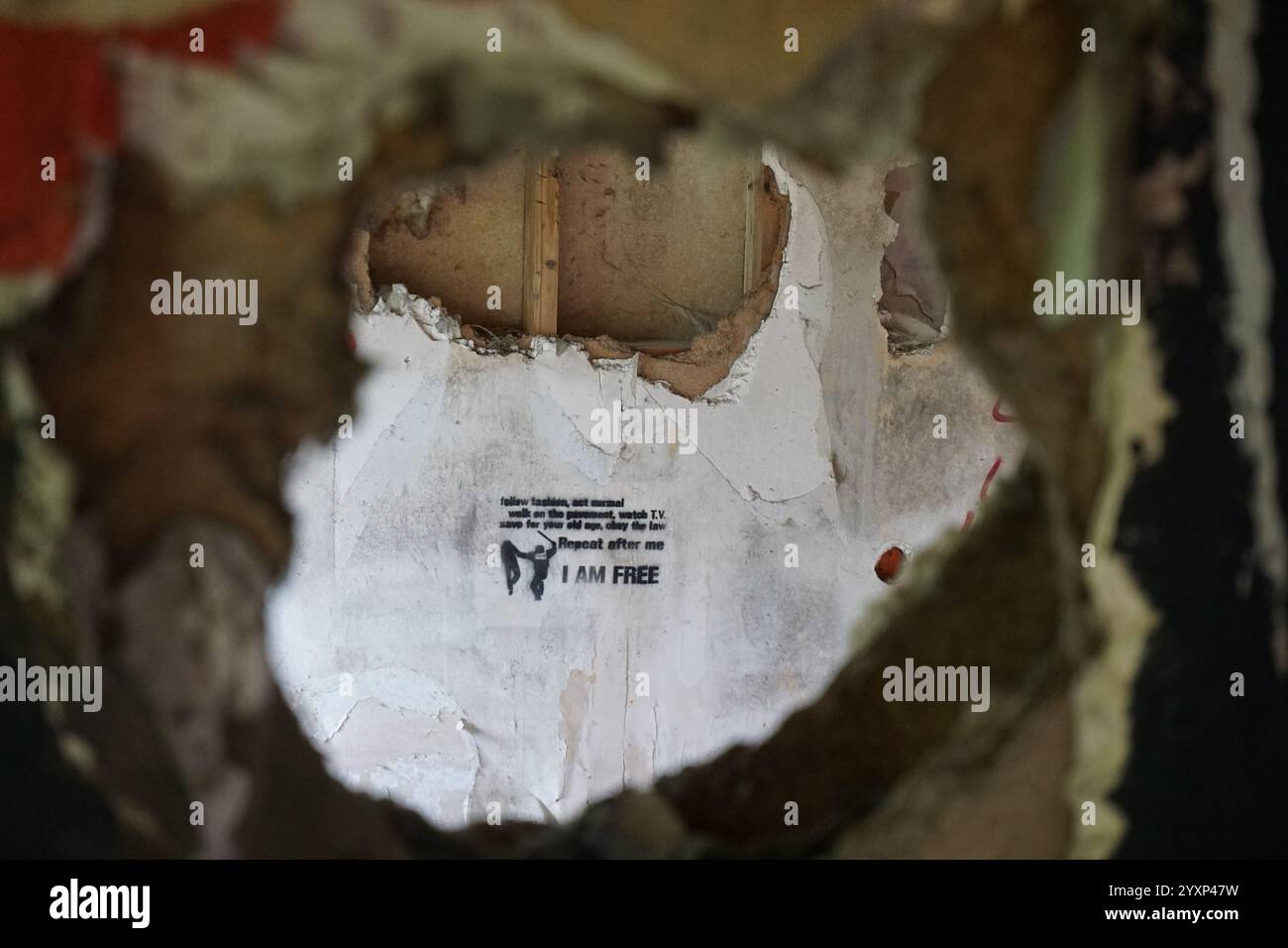 A wall with a hole in it and a graffiti saying I am free. The graffiti ...