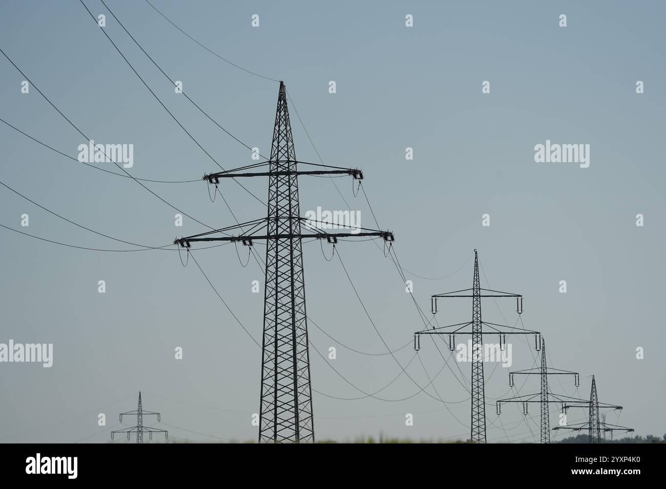 A series of tall power lines are seen in the sky. The power lines are ...