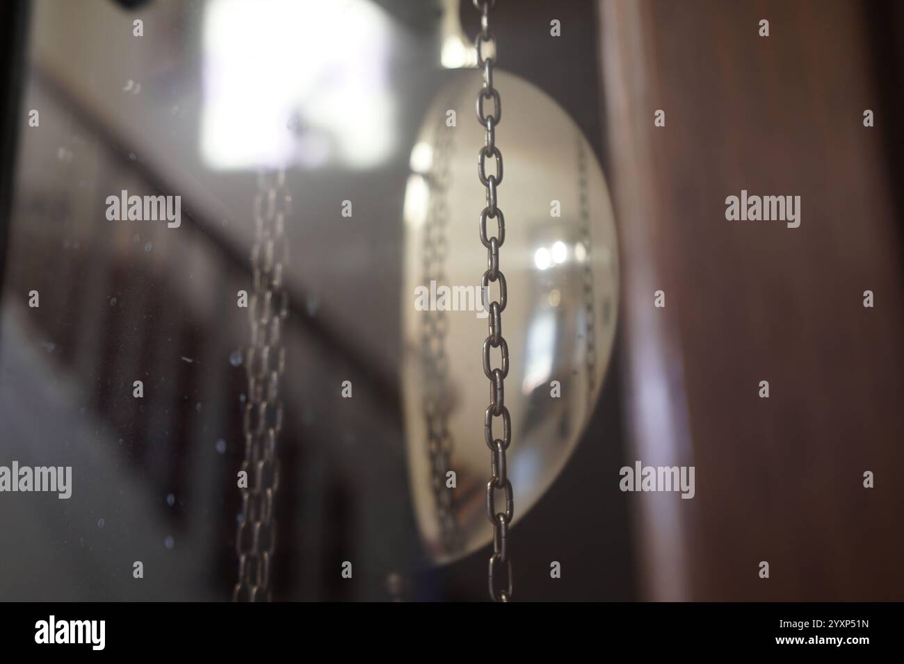 A silver chain hangs from a clock, and it is visible in the reflection ...
