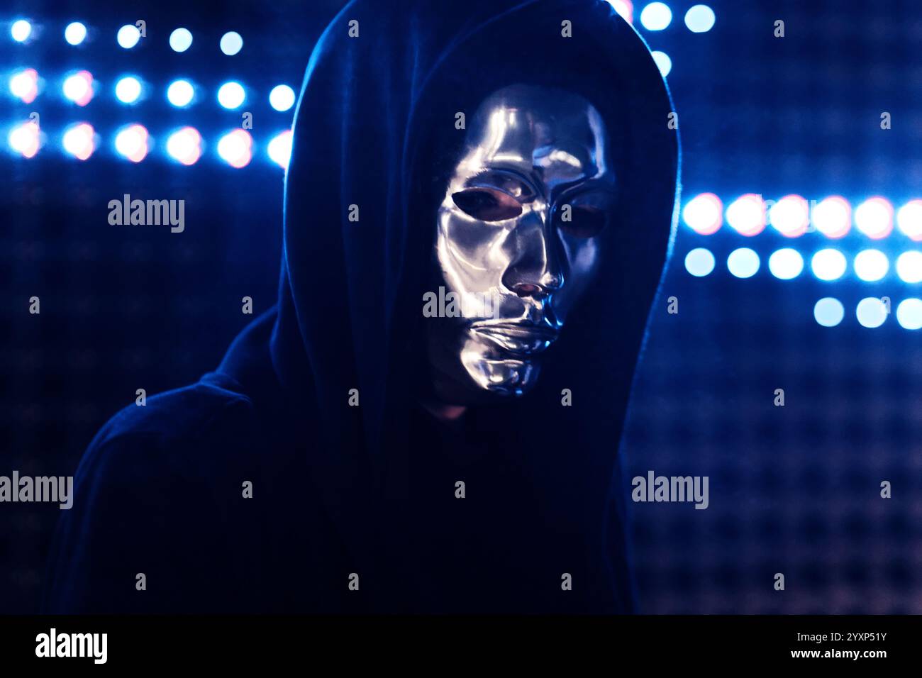 A person is wearing a silver mask and a black hoodie, standing in front ...