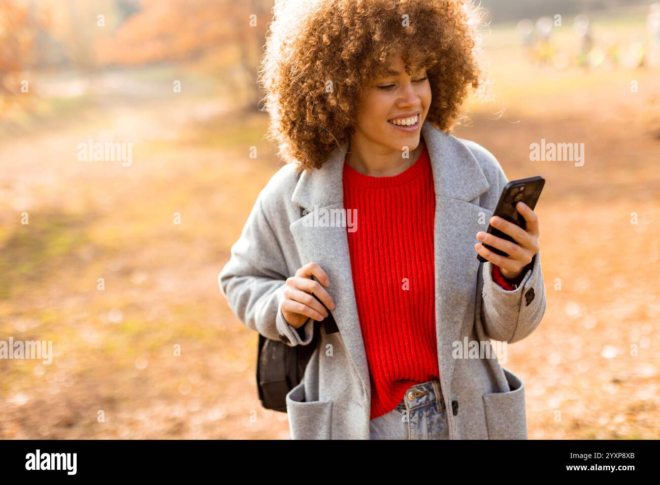 A cheerful individual with curly hair smiles brightly as she engages ...