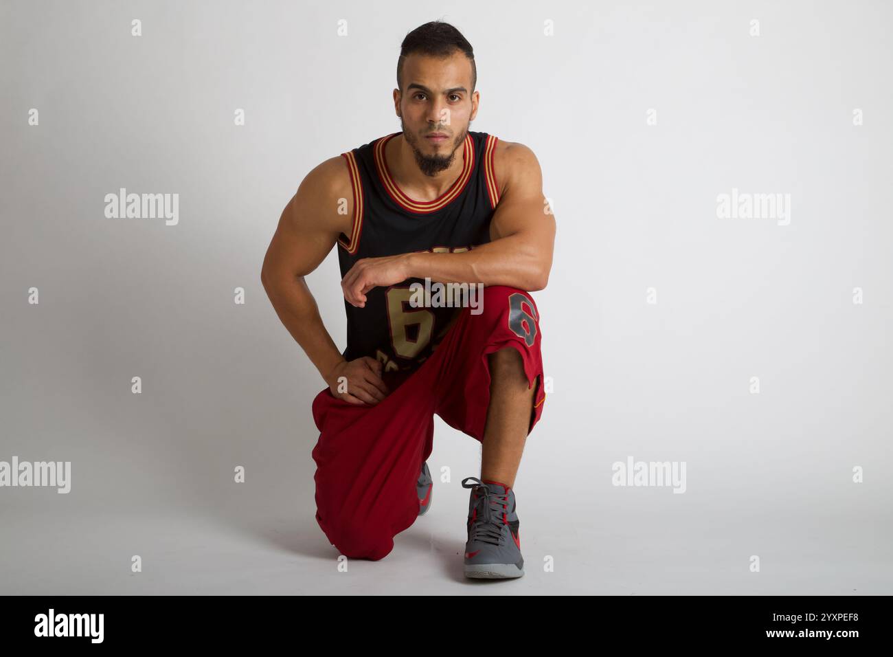 Man on one knee in basketball kit Stock Photo - Alamy