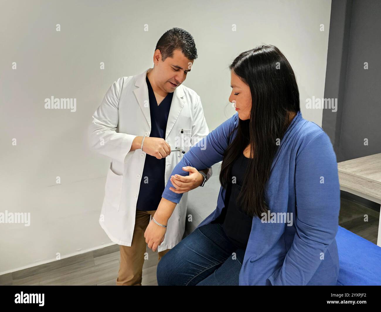 Dark-skinned male doctor attends to Latin woman patient neurological ...