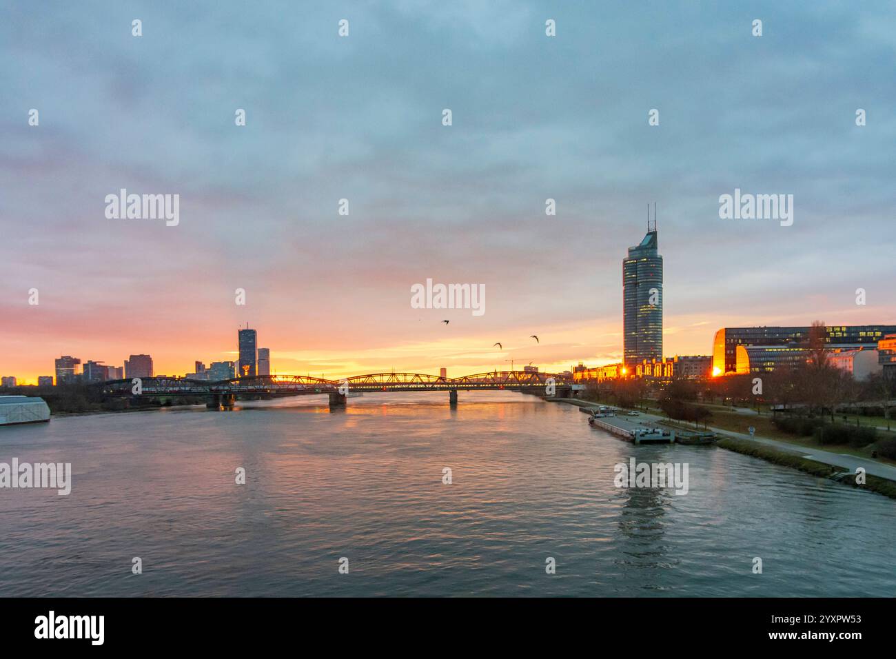 fiery sunrise at river Donau Danube, bridge Nordbahnbrücke, high-rises ...