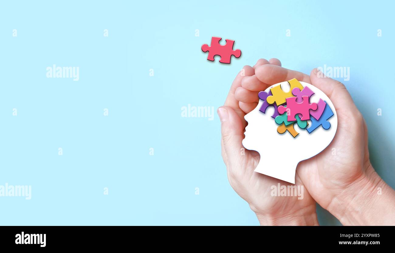 Hands holding paper head with jigsaw puzzle, Autism spectrum disorder ...