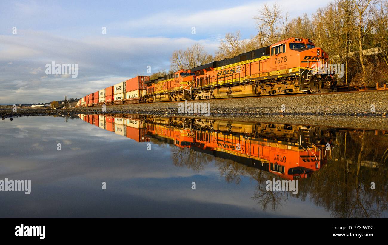 Seattle, WA, USA - December 16, 2024; BNSF intermodal container feight train reflecting in ...