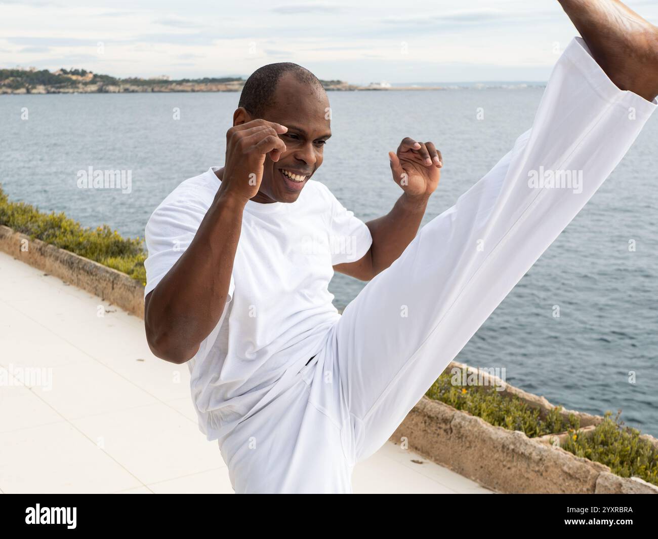 Brazilian man practicing capoeira martial arts kick near a scenic ...