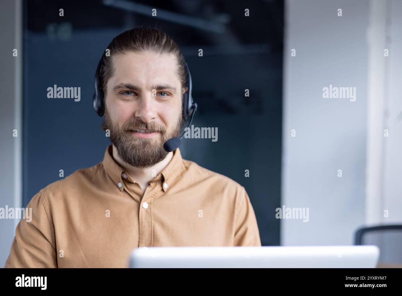 A friendly customer service representative wearing a headset and smiling while working remotely ...