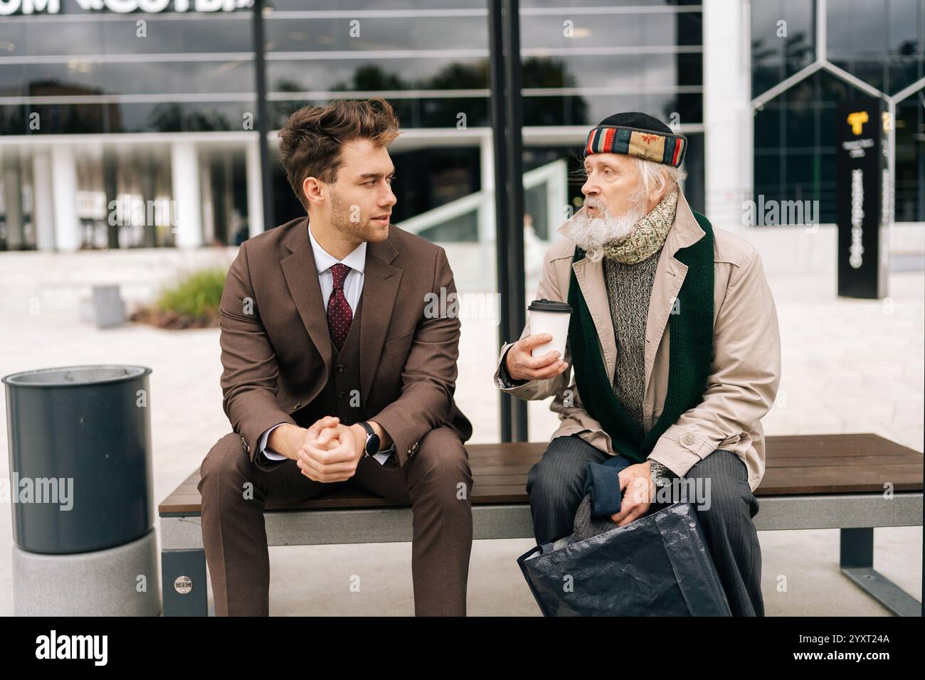 Portrait of businessman in suit listening story to elderly homeless man ...