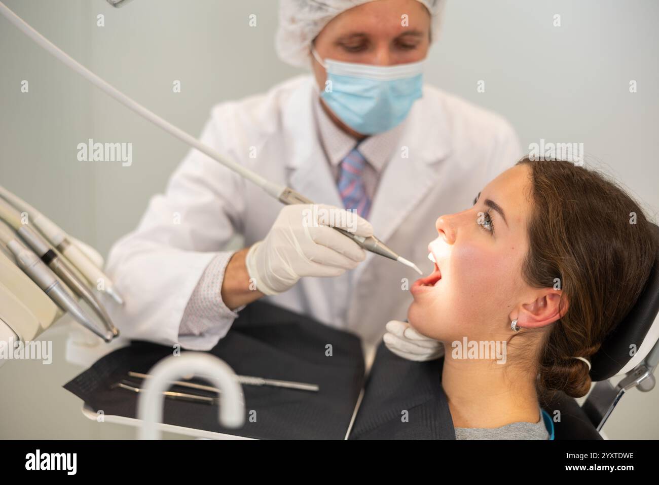 Adult male dentist cleaning teeth of female patient Stock Photo - Alamy